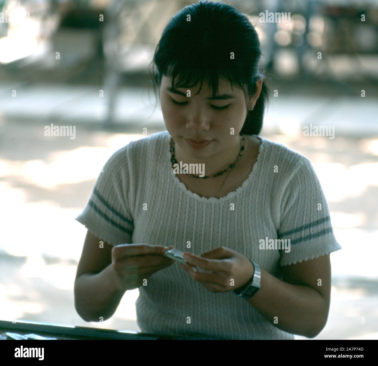 A young Vietnamese woman makes souvenirs to sell to tourists in the ...