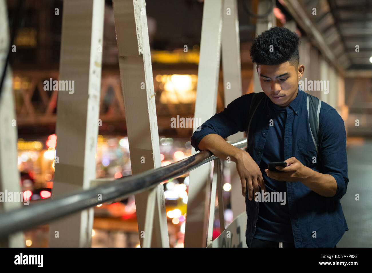 Young Asian man using phone on the footbridge at night Stock Photo - Alamy