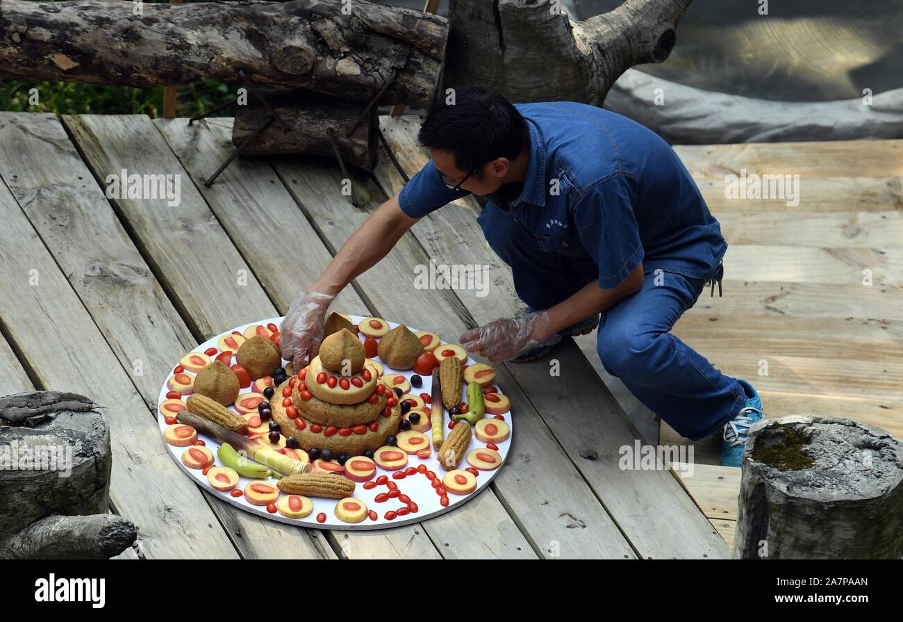 A Chinese worker displays a birthday cake made with fodder and fruits ...