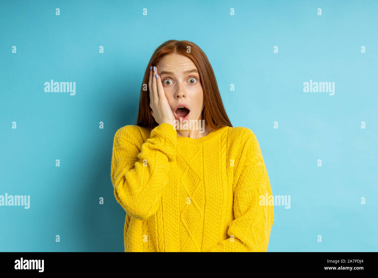Portrait of shocked stunned young ginger female looking at camera with ...