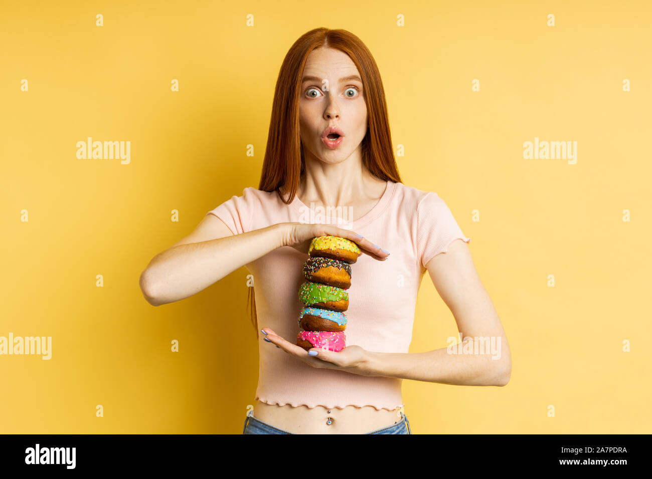 Surprised redhead woman with colorful donuts. Shot of caucasian female ...