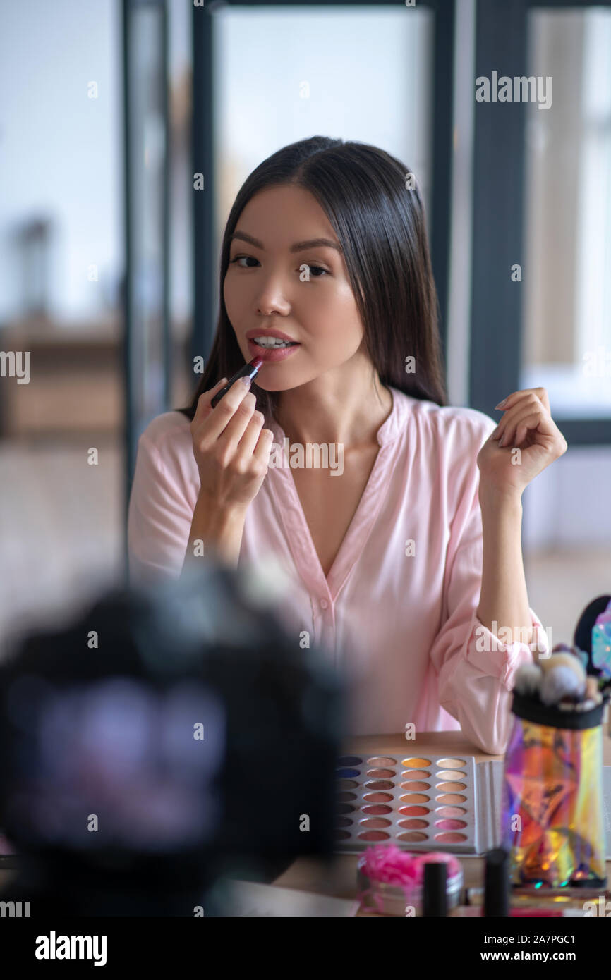 Dark-eyed woman using lipstick while finishing makeup Stock Photo - Alamy