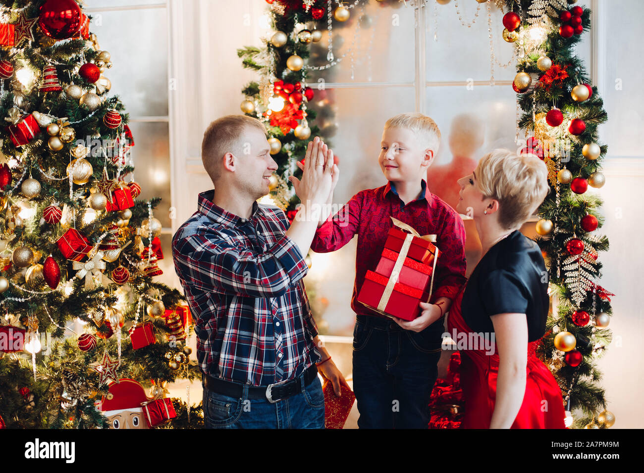 Son gives father high five while holding Christmas presents against ...