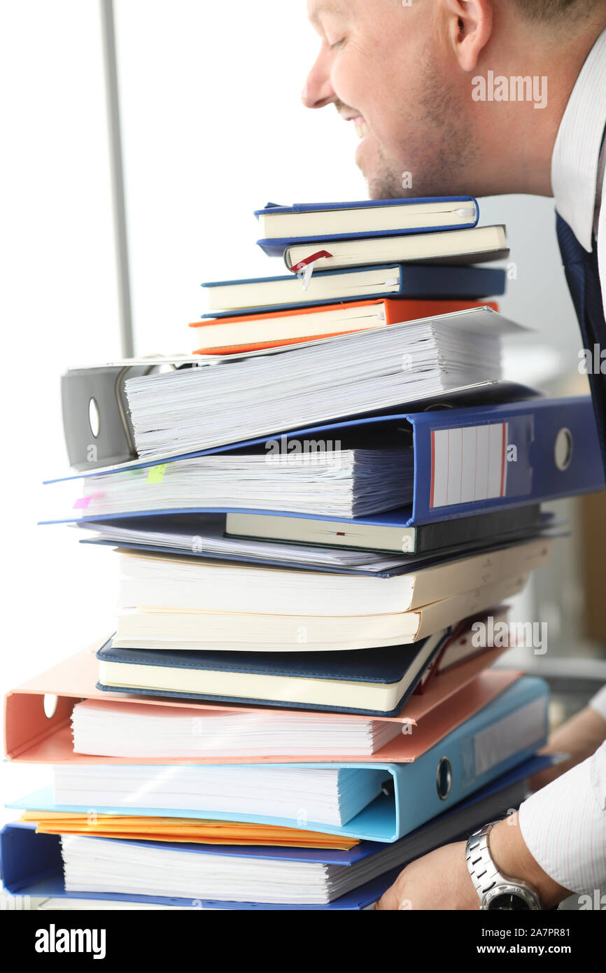 Office worker trying to lift huge pile of documents Stock Photo - Alamy