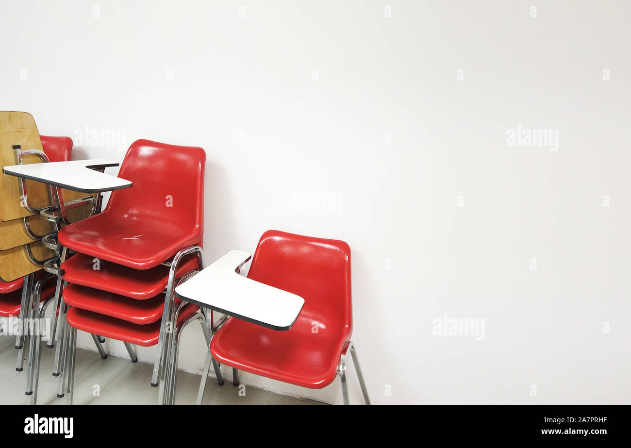 Red plastic folding chair stack on classroom background Stock Photo - Alamy