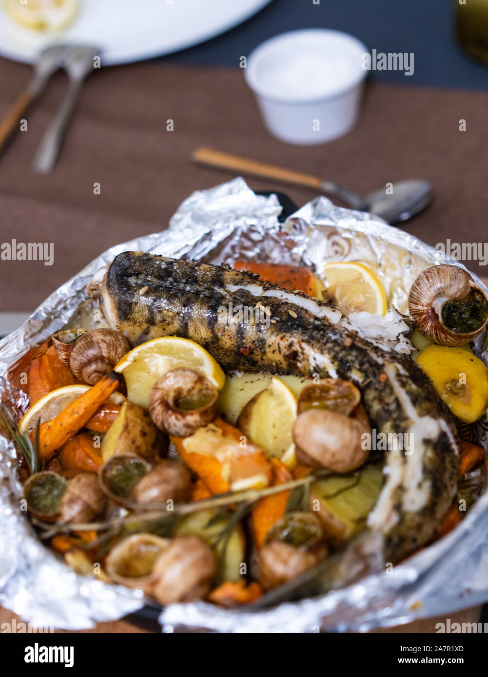 Grilled fish, sea snails with lemon and vegetables Stock Photo - Alamy