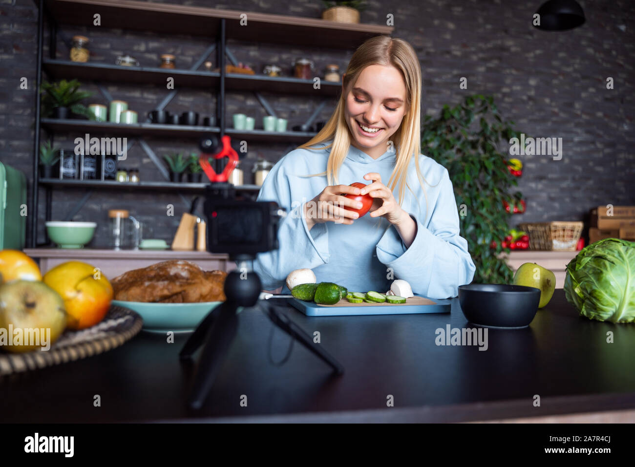 Young beautiful blonde takes on videos as she cooks in the kitchen ...