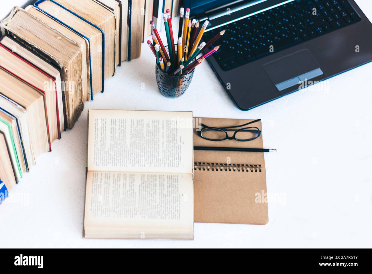Open textbook, notebook, laptop computer, stack of books education back ...