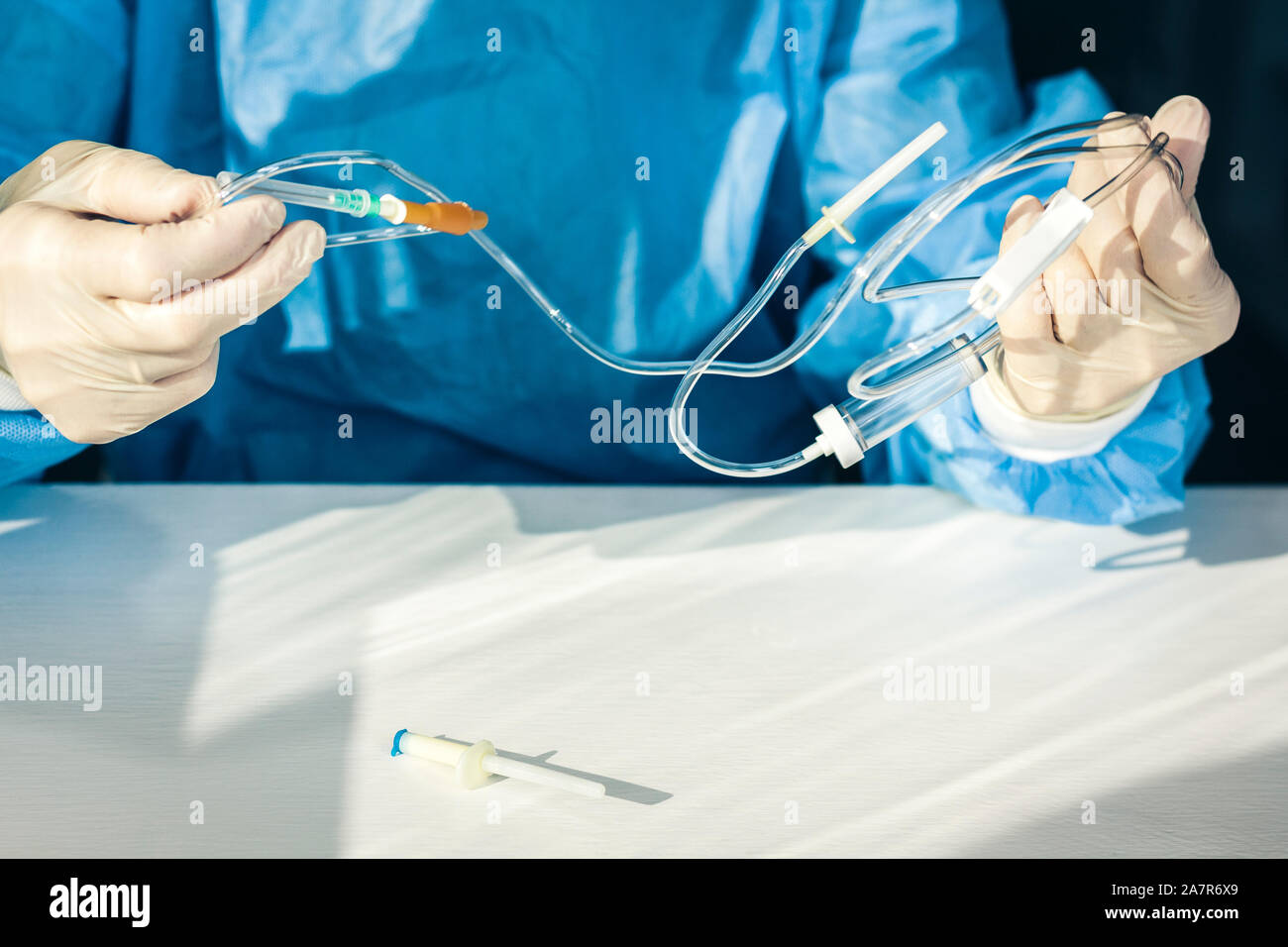 doctor in a blue surgical gown and mask holds in his hand a medical ...