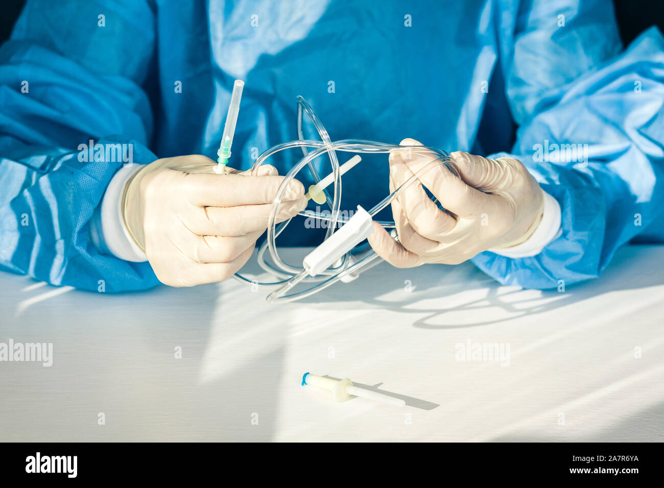doctor in a blue surgical gown and mask holds in his hand a medical ...