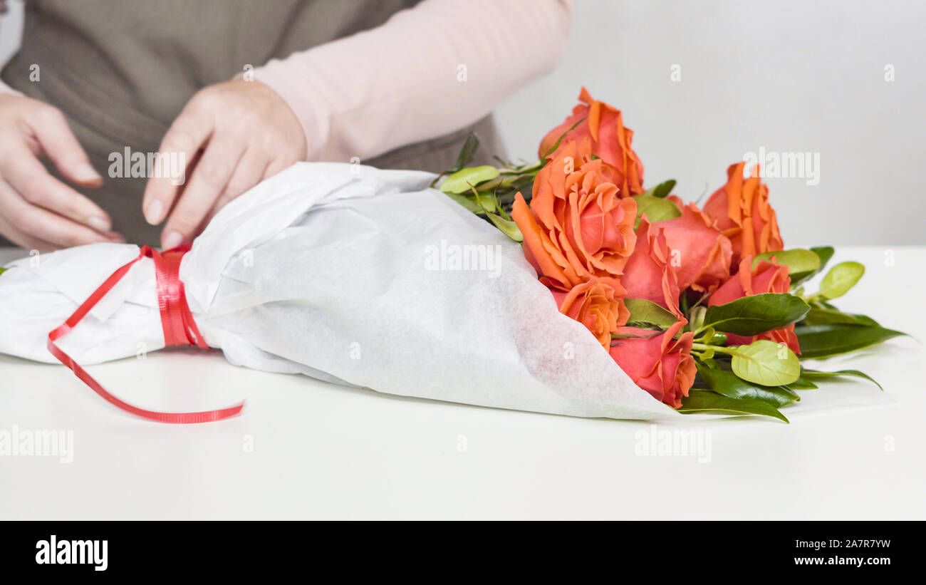 Florist wrapping red roses into a beautiful bouquet Stock Photo - Alamy