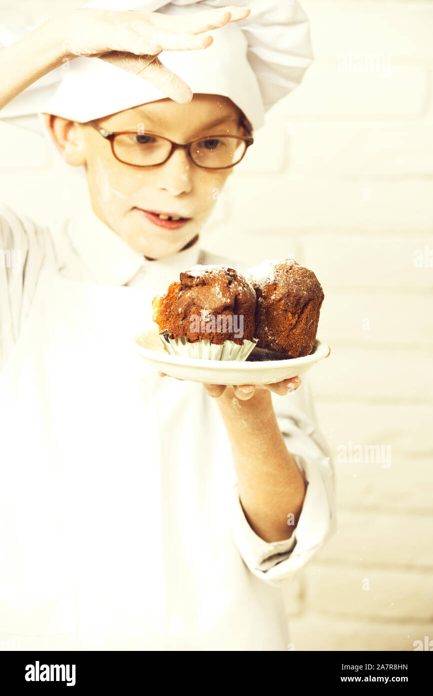 young boy cute cook chef in white uniform and hat on stained face flour ...