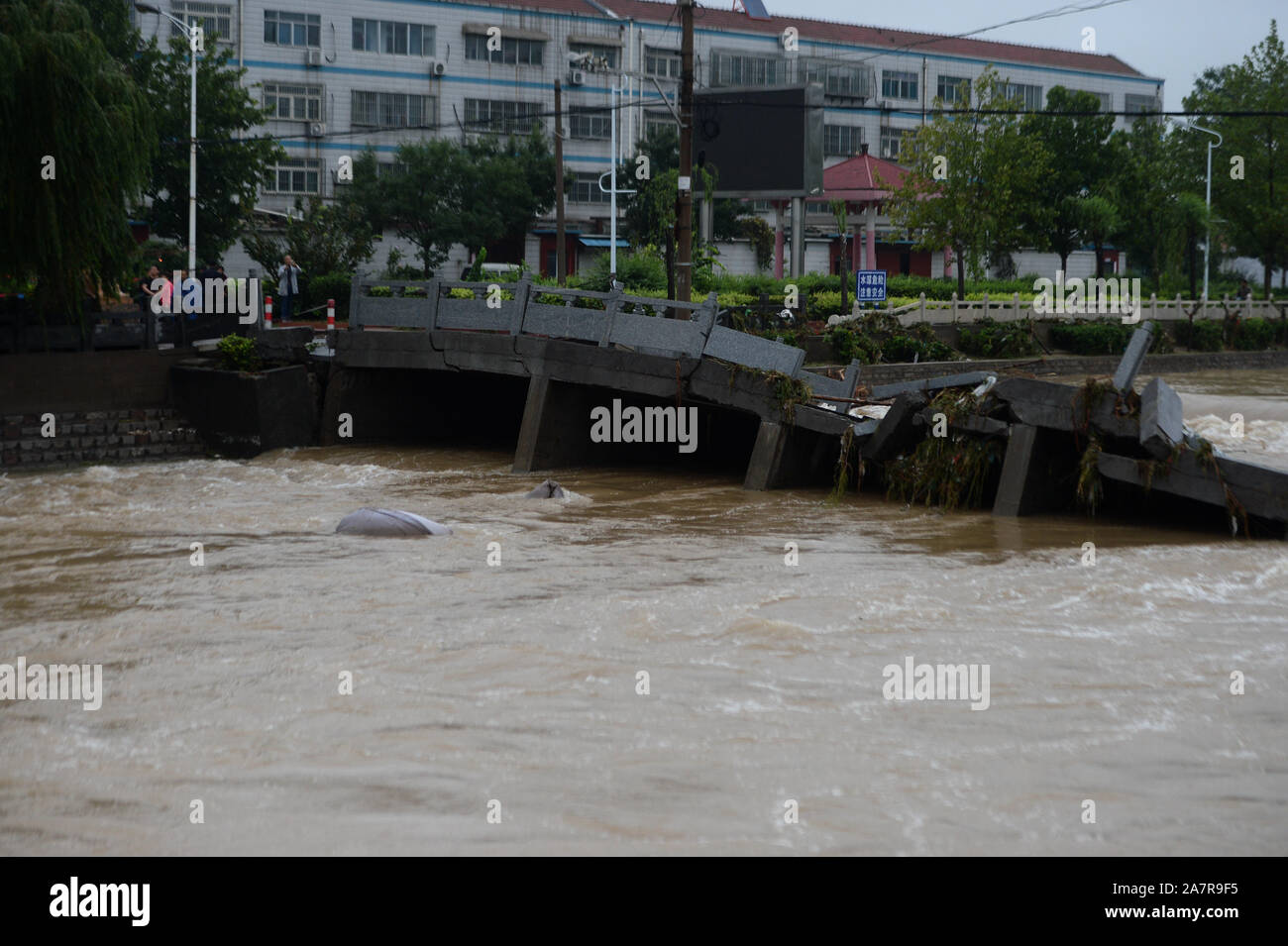 A bridge is devastated by the floodwater due to rainstorms caused by ...