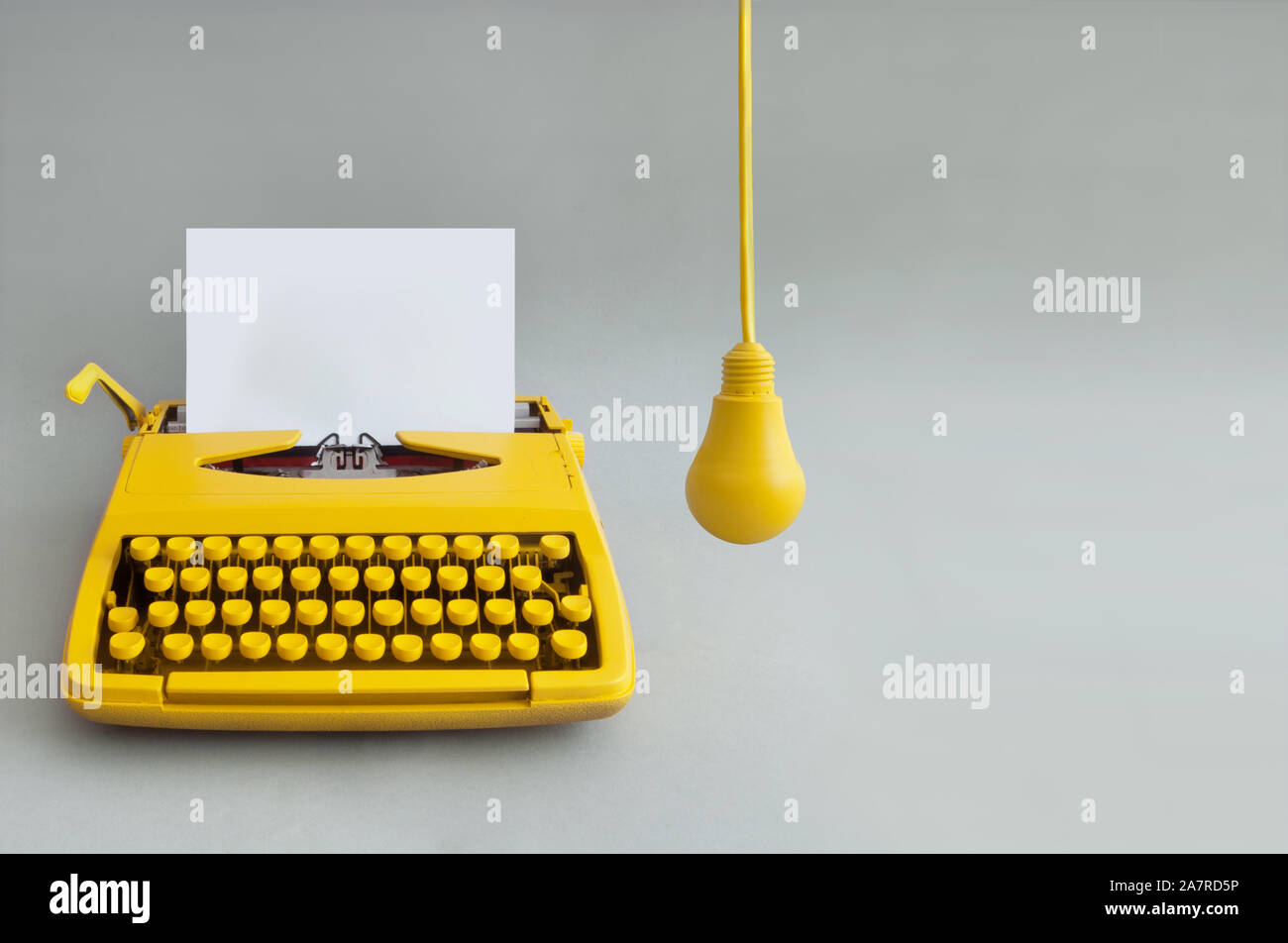 Retro typewriter with yellow hanging light bulb, representing ...