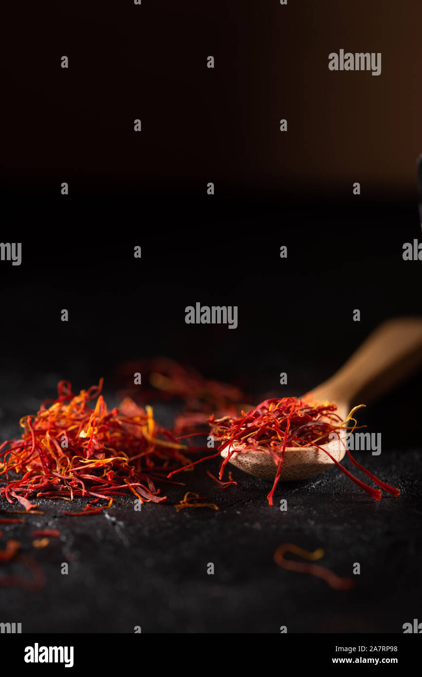 Saffron spices heap and wooden spoon on black slate stone table ...