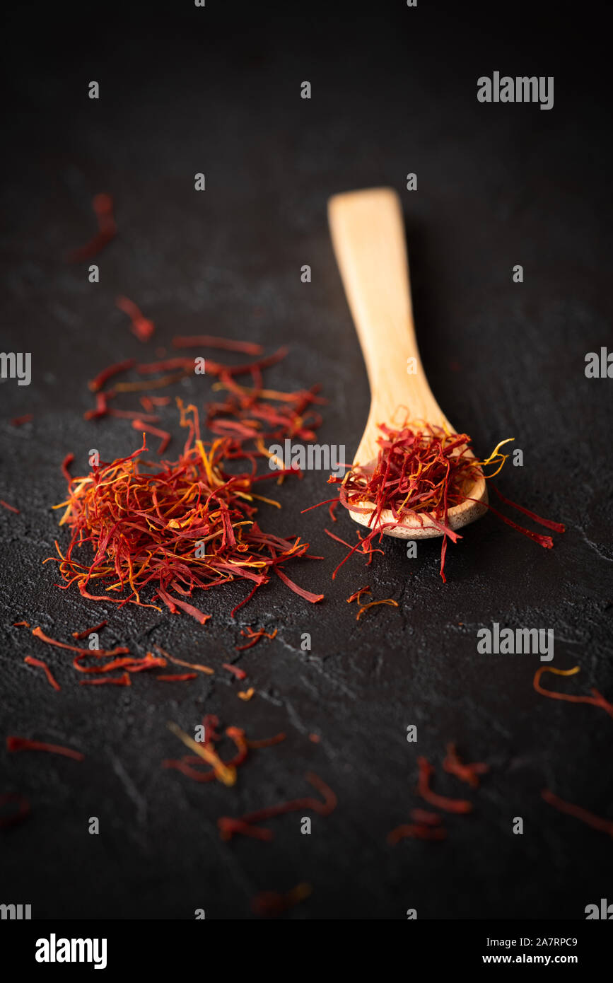 Saffron spices threads in wooden spoon on black slate stone table ...