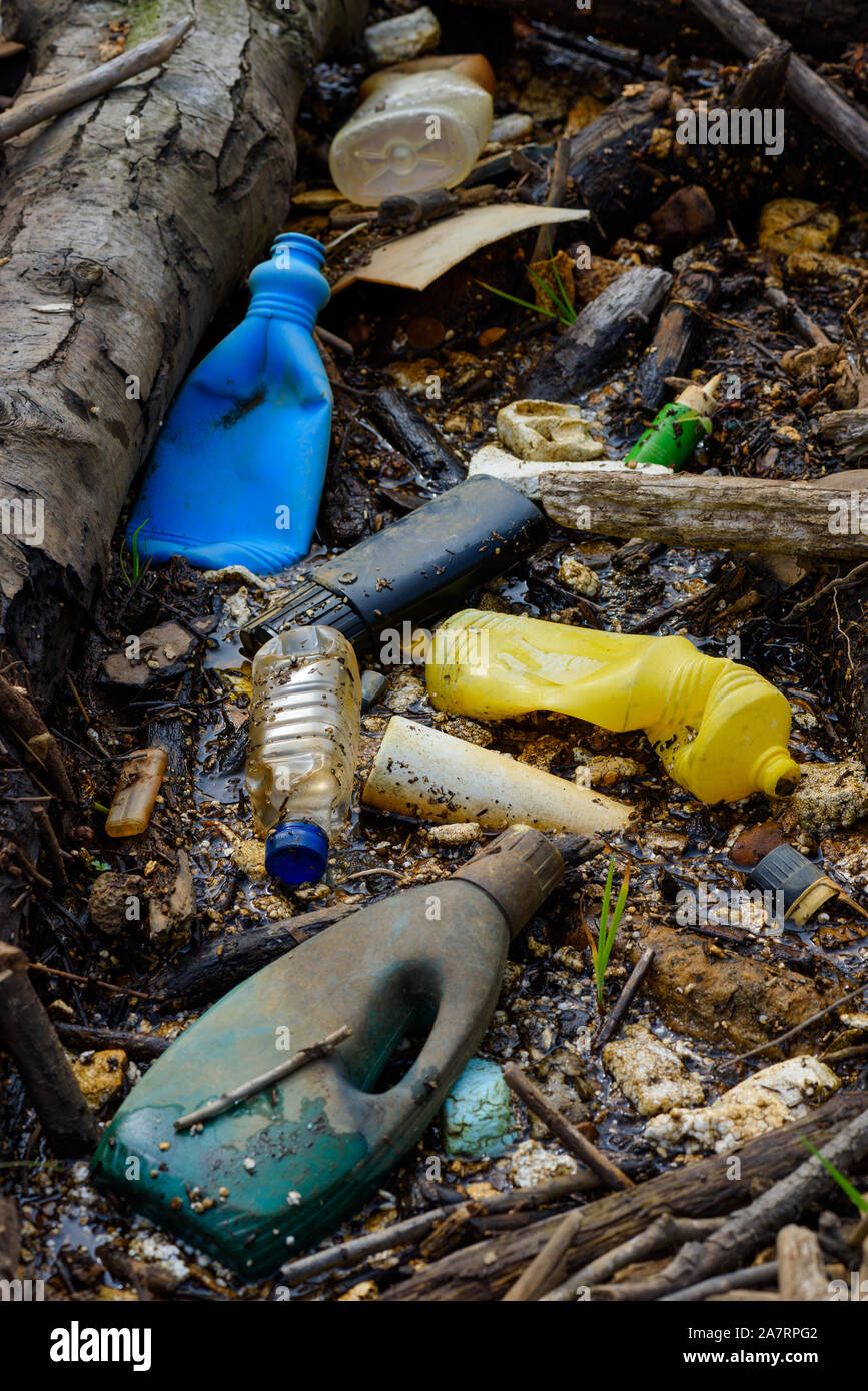 Plastic pollution muddy puddle with bottles waste and styrofoam on ...