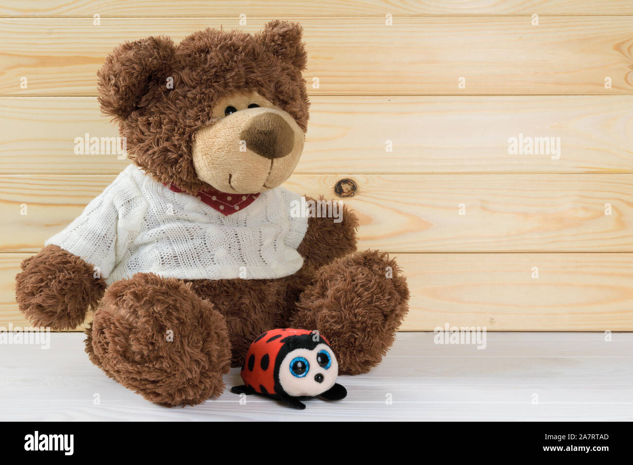 toy brown teddy bear sits on a white wooden table on a background of ...