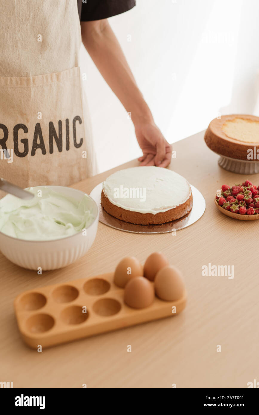 Pastry chef prepare putting cream on sponge cake. Making sponge cake ...