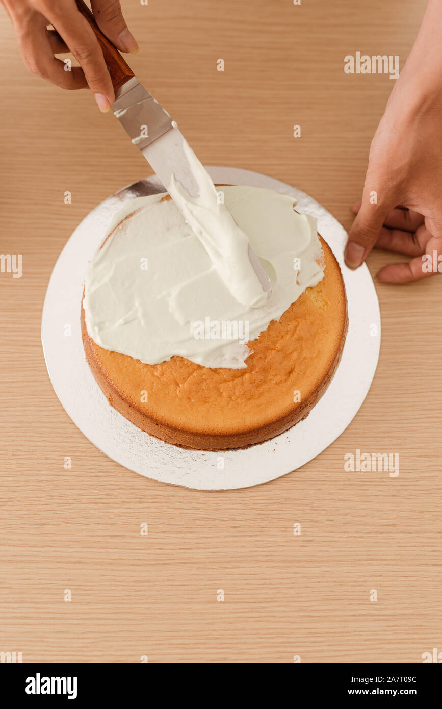 Putting cream on sponge cake over wood table or background Stock Photo ...