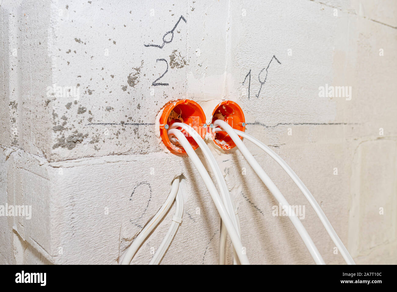 Orange, round junction box mounted in the white wall with protruding ...