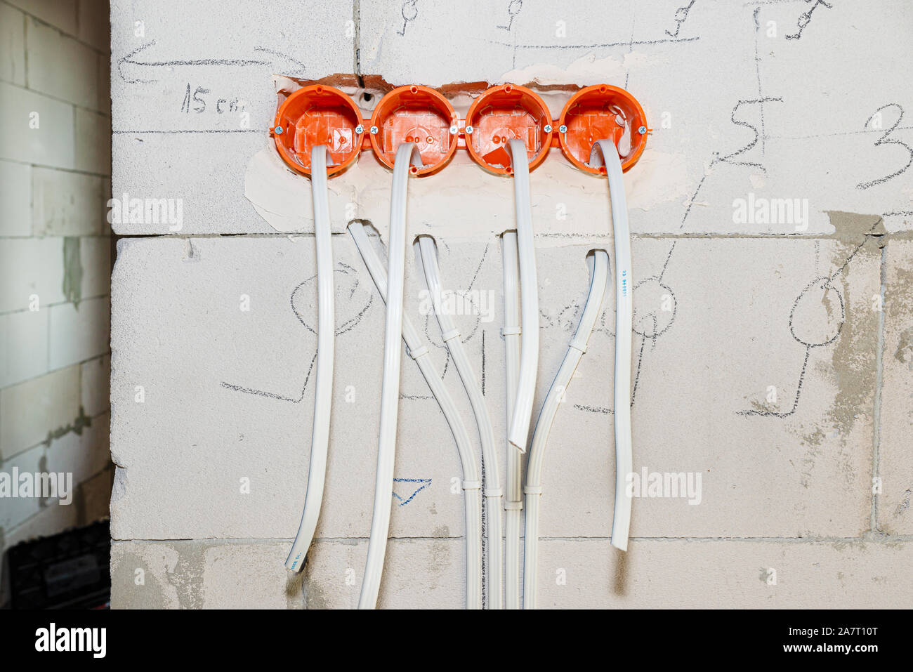 Orange, round junction box mounted in the white wall with protruding ...