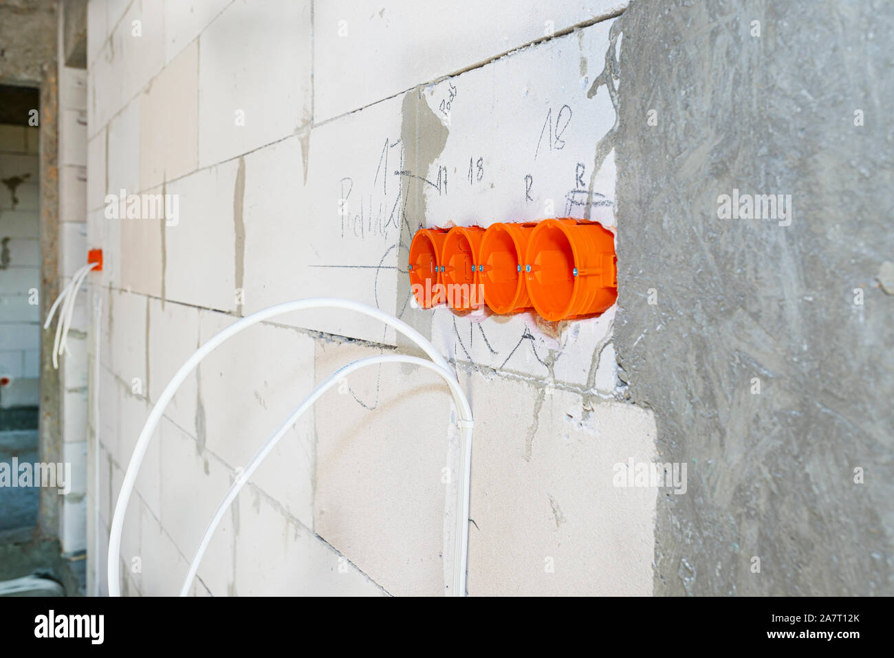 Orange, round junction box mounted in the white wall with protruding ...