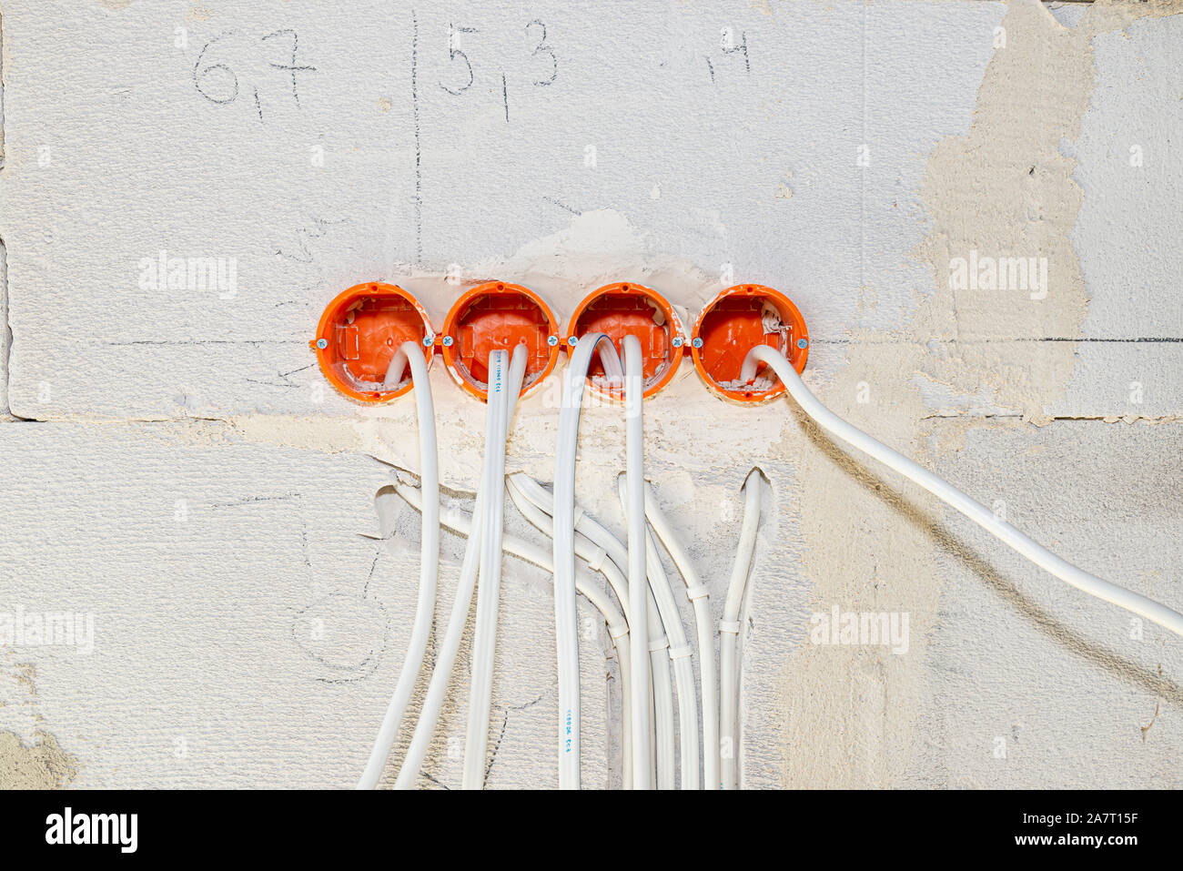 Orange, round junction box mounted in the white wall with protruding ...