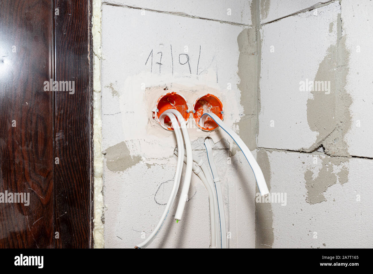 Orange, round junction box mounted in the white wall with protruding ...