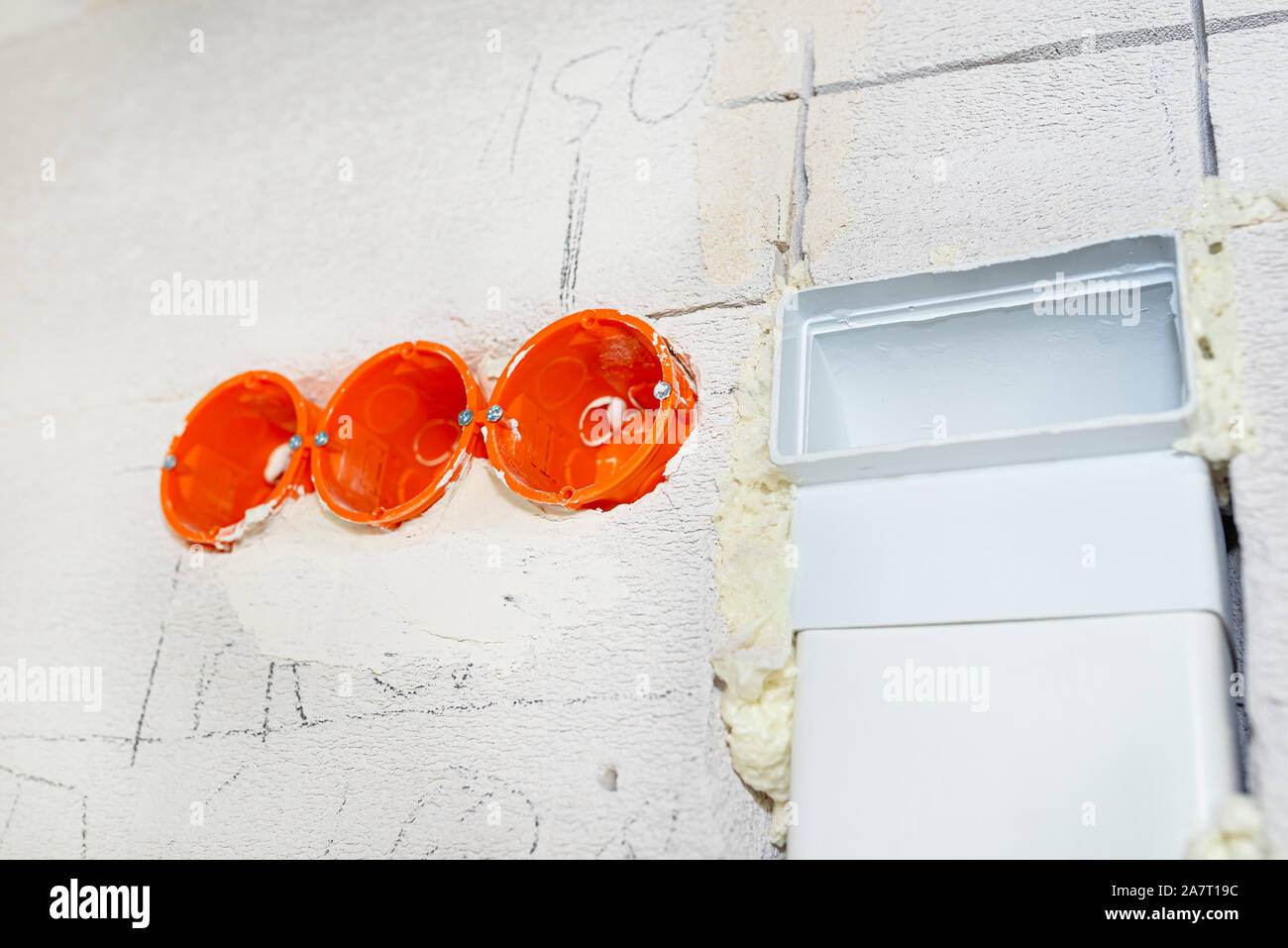 Orange, round junction box mounted in the white wall with protruding ...