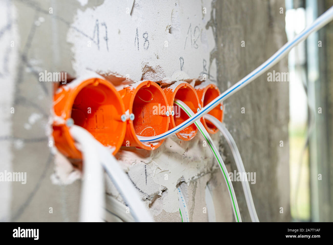 Orange, round junction box mounted in the white wall with protruding ...