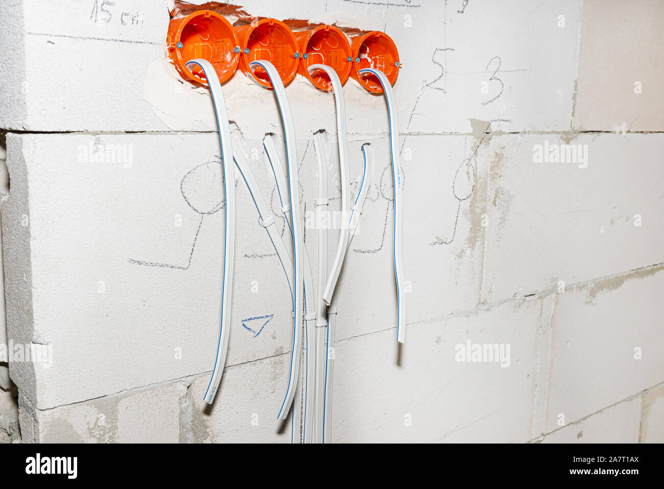 Orange, round junction box mounted in the white wall with protruding ...