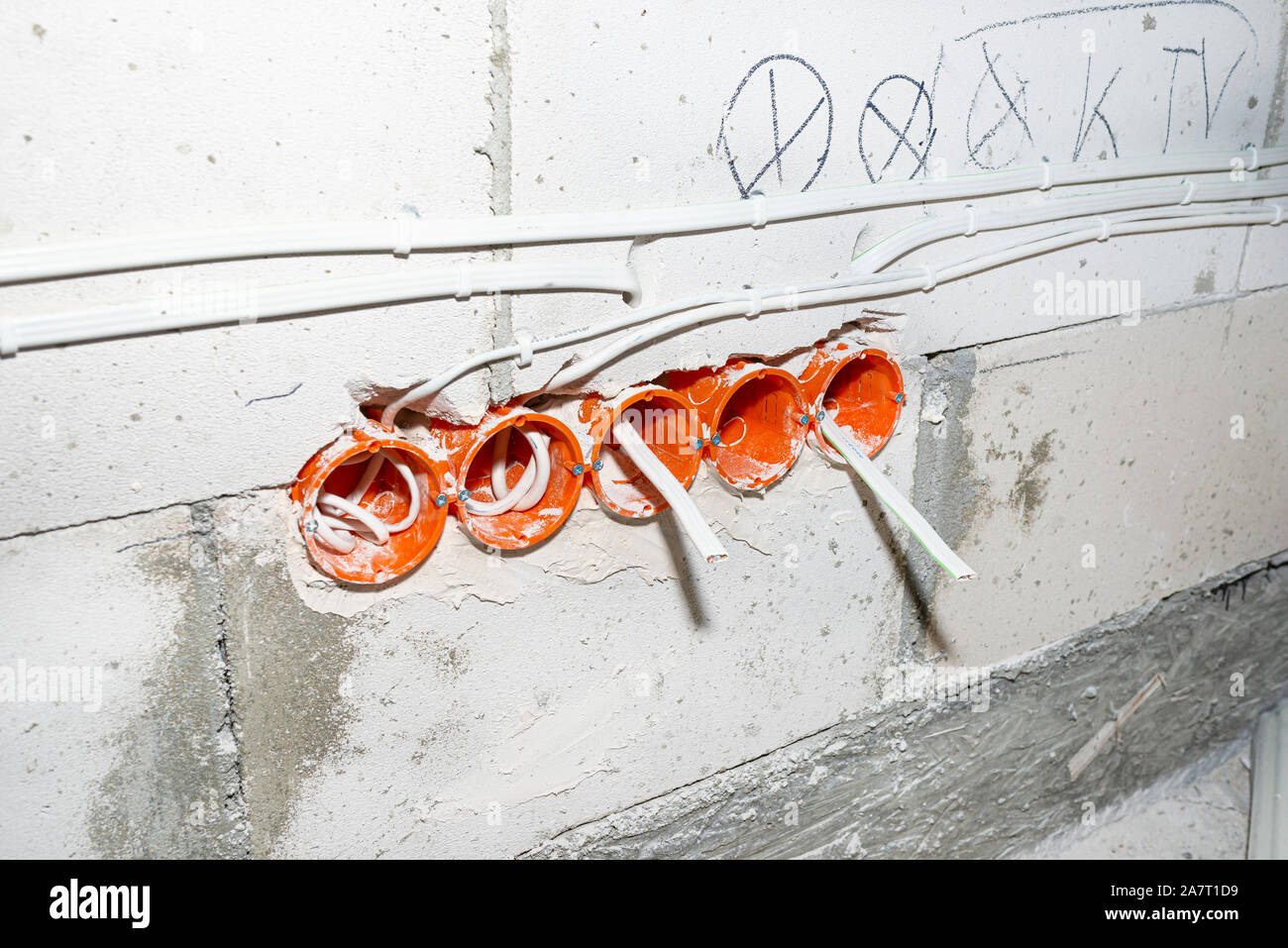 Orange, round junction box mounted in the white wall with protruding ...