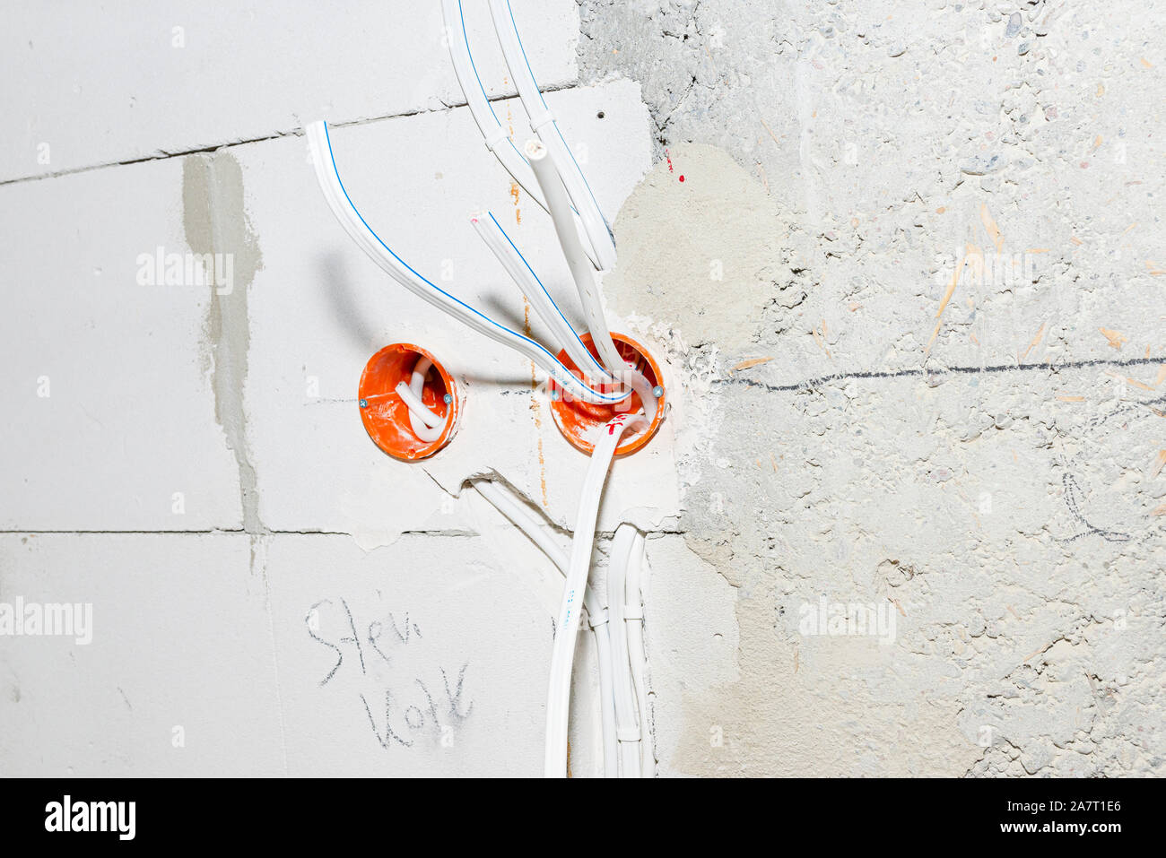 Orange, round junction box mounted in the white wall with protruding ...