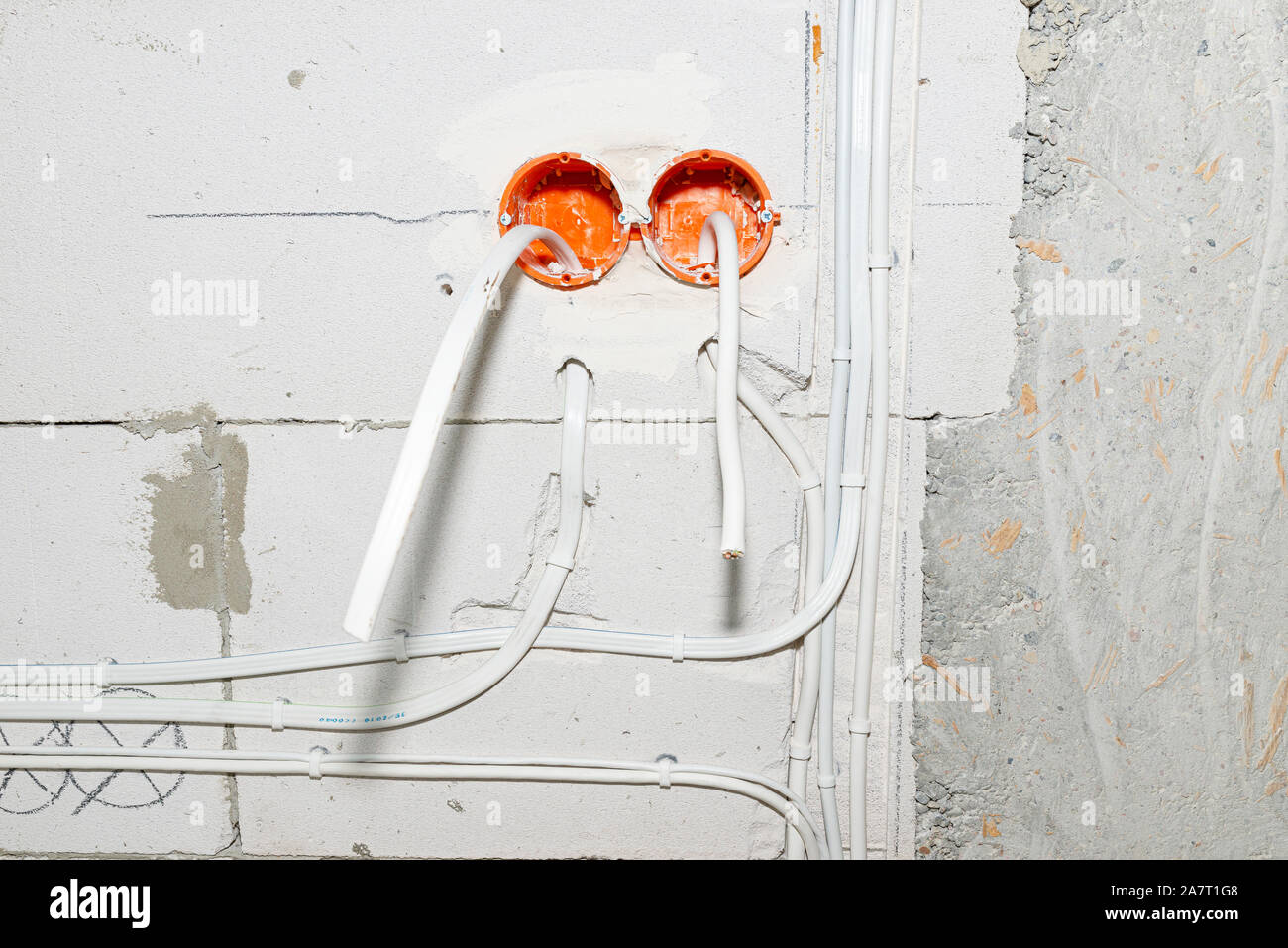 Orange, round junction box mounted in the white wall with protruding ...