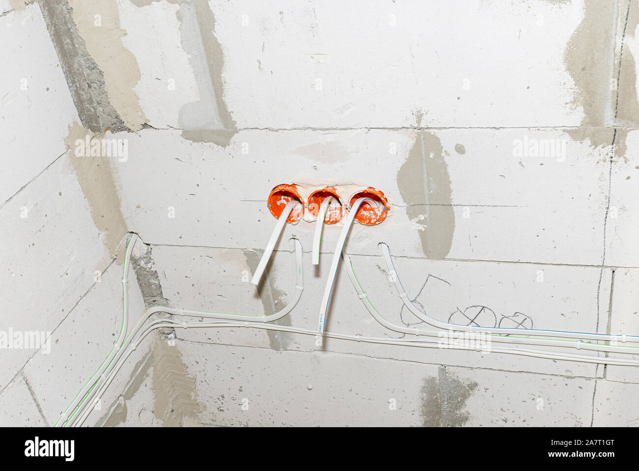 Orange, round junction box mounted in the white wall with protruding ...