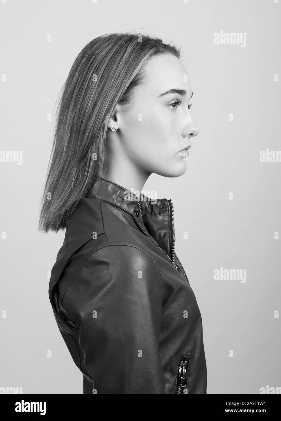 Profile portrait of a young woman wearing a leather jacket in black and ...