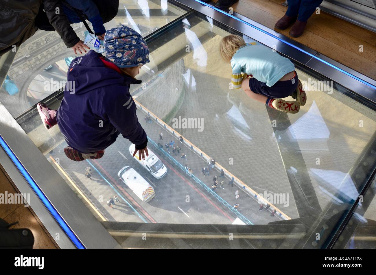 Two young boys looking down through glass walkway of Tower Bridge at ...