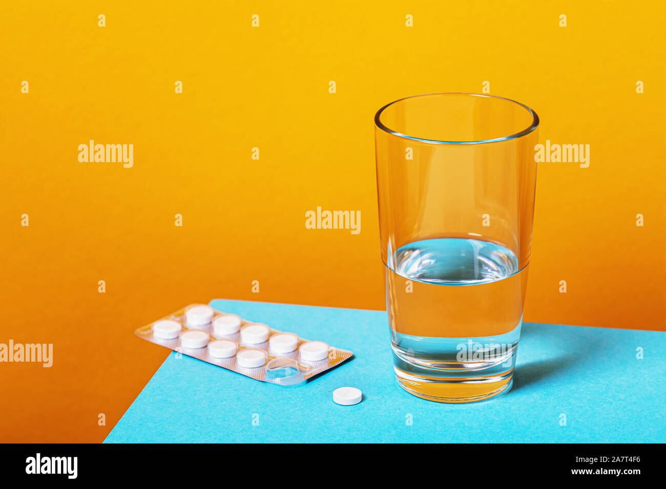 Aspirin pills and a glass of water on the table. Treatment of cold ...