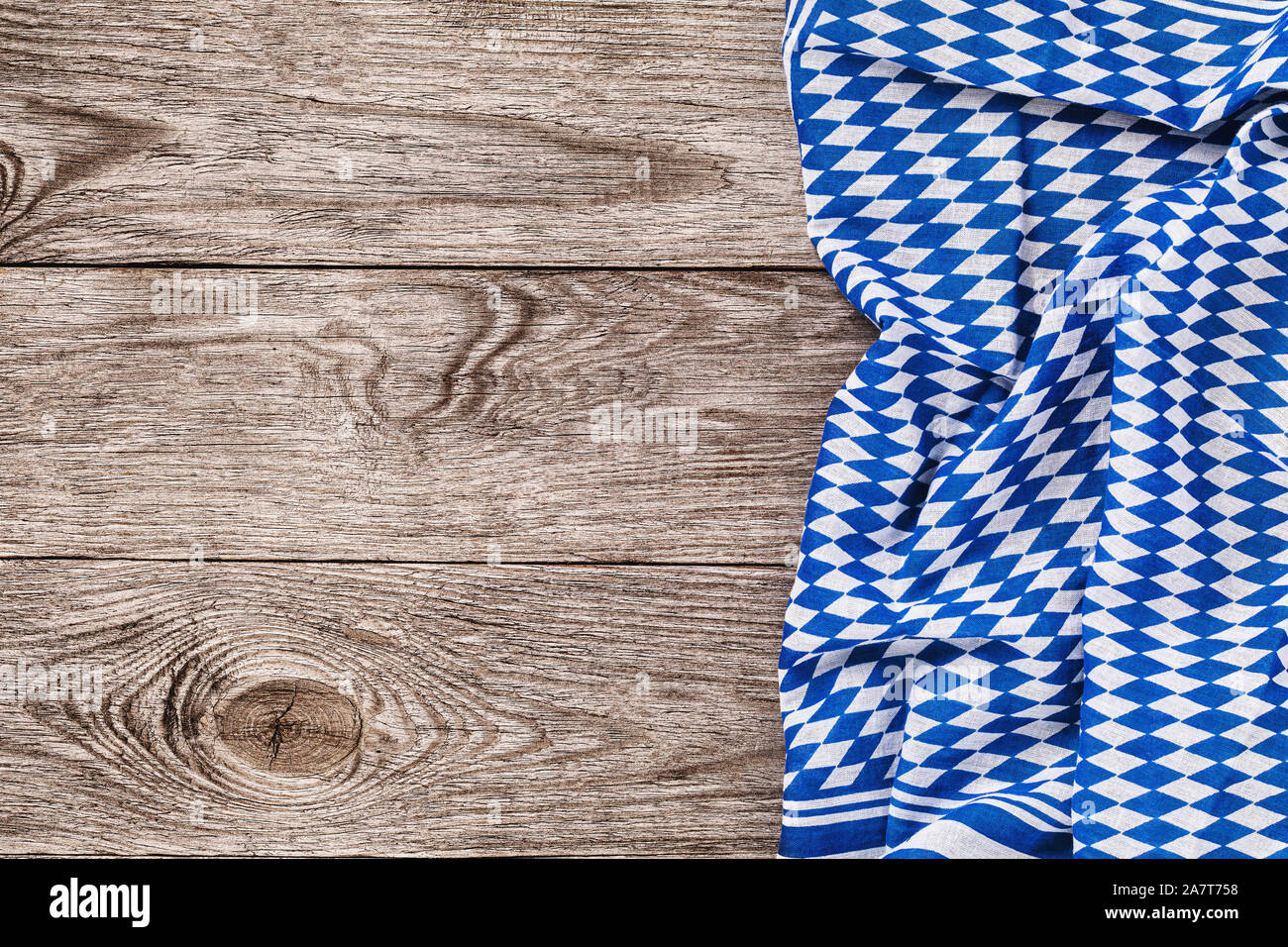 Blue - white textile napkin on the right side of a wooden table, top ...