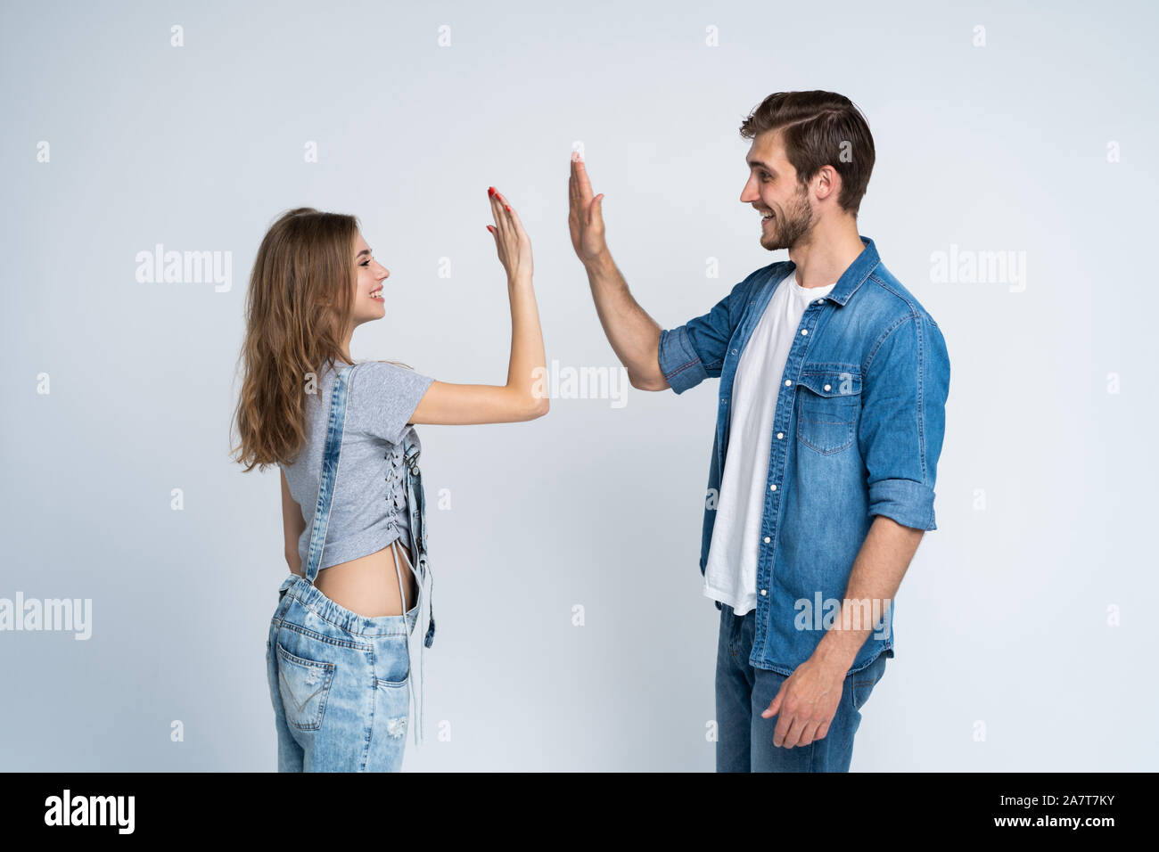 Portrait of a cheery young couple giving high five over gray background ...
