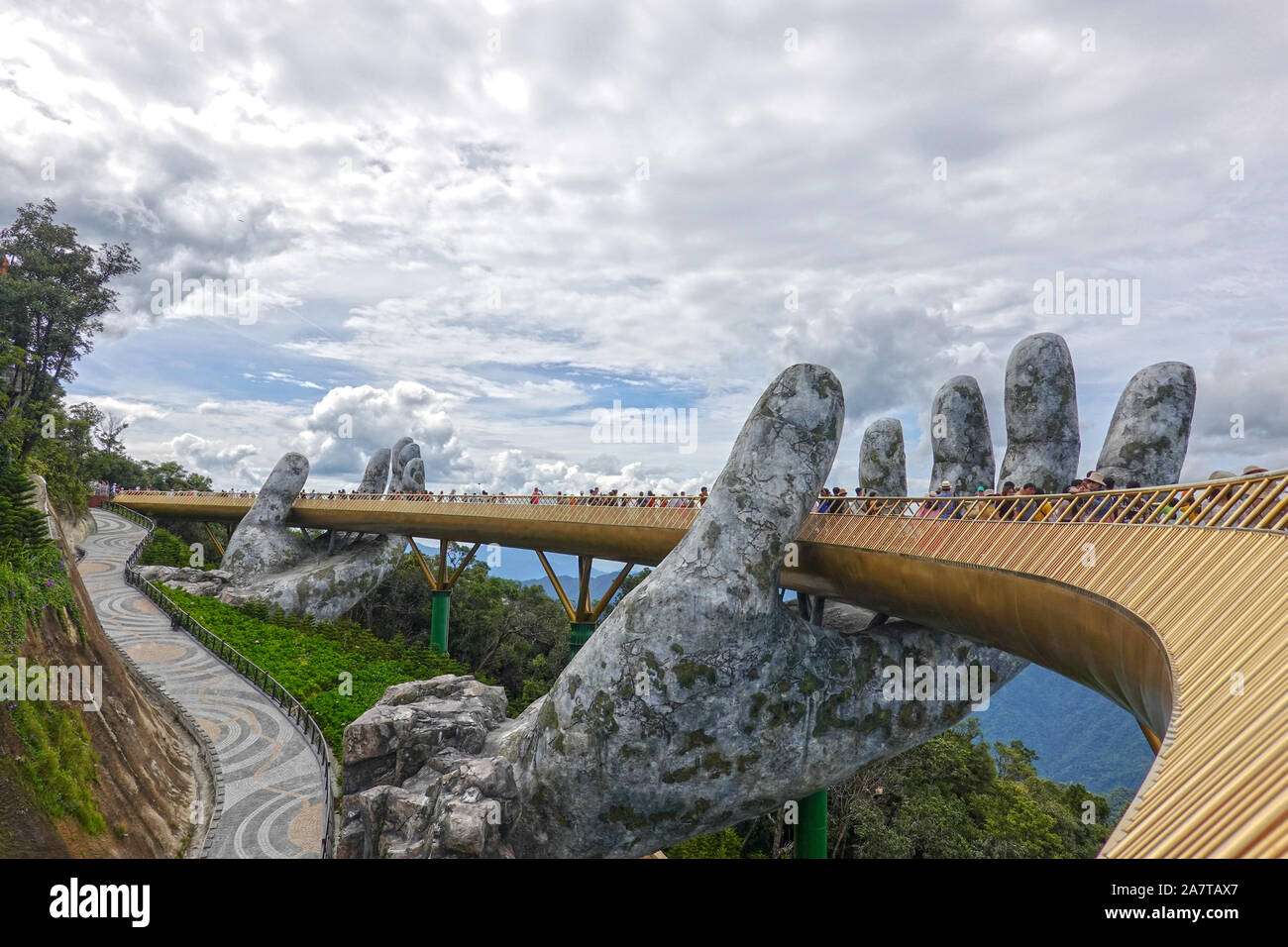 Tourists visit the Golden Bridge held up by hand statues surrounded by ...
