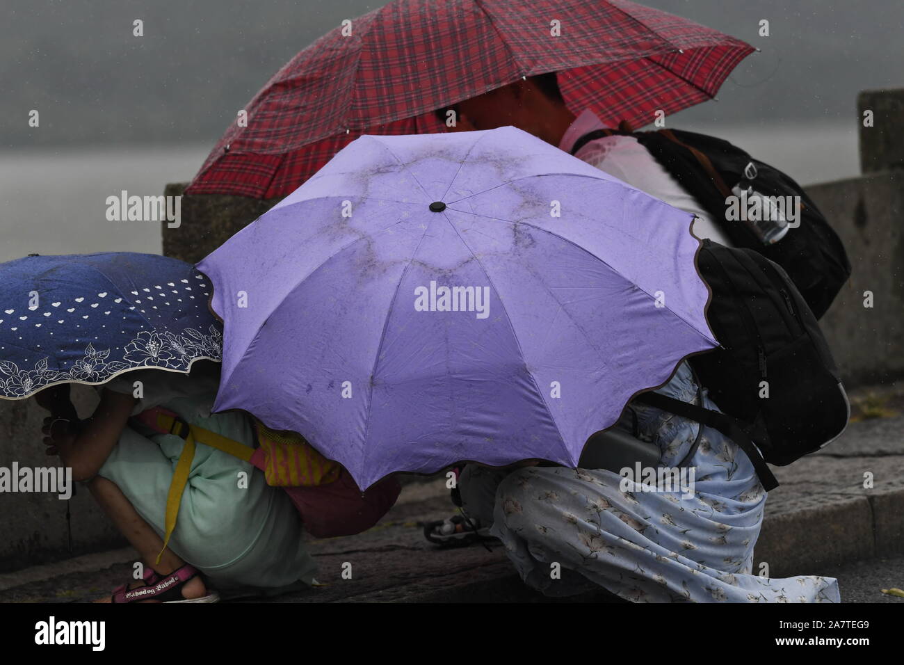 Tourists struggle with their umbrellas in heavy rain and strong wind ...
