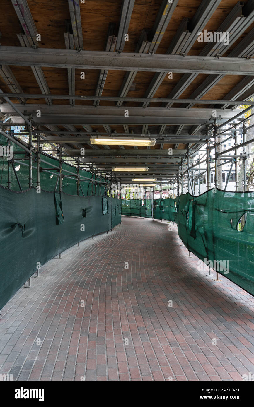 pedestrian path through a construction site with green fabric sides ...