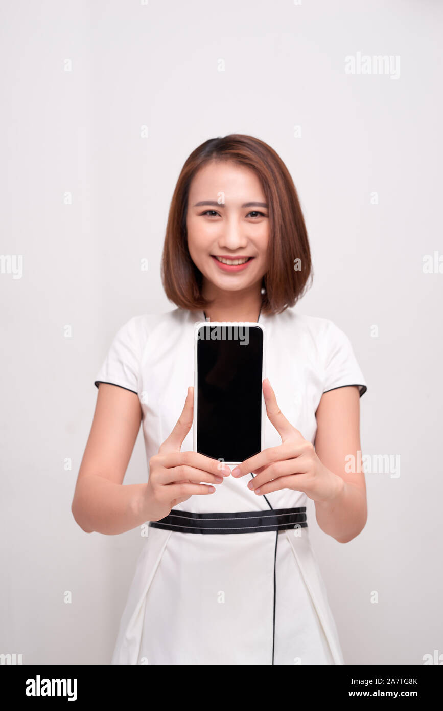Beautiful Asian woman holding blank screen smartphone on white ...