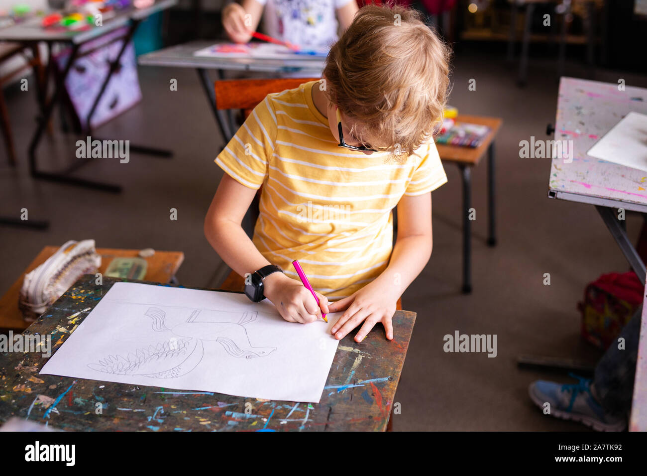 Blonde boy with glasses drawing. Group of elementary school pupils in ...