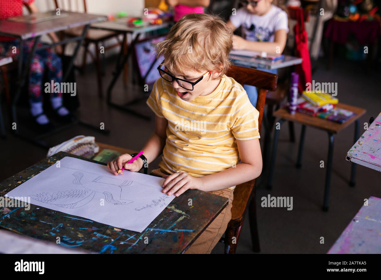 Blonde boy with glasses drawing. Group of elementary school pupils in ...