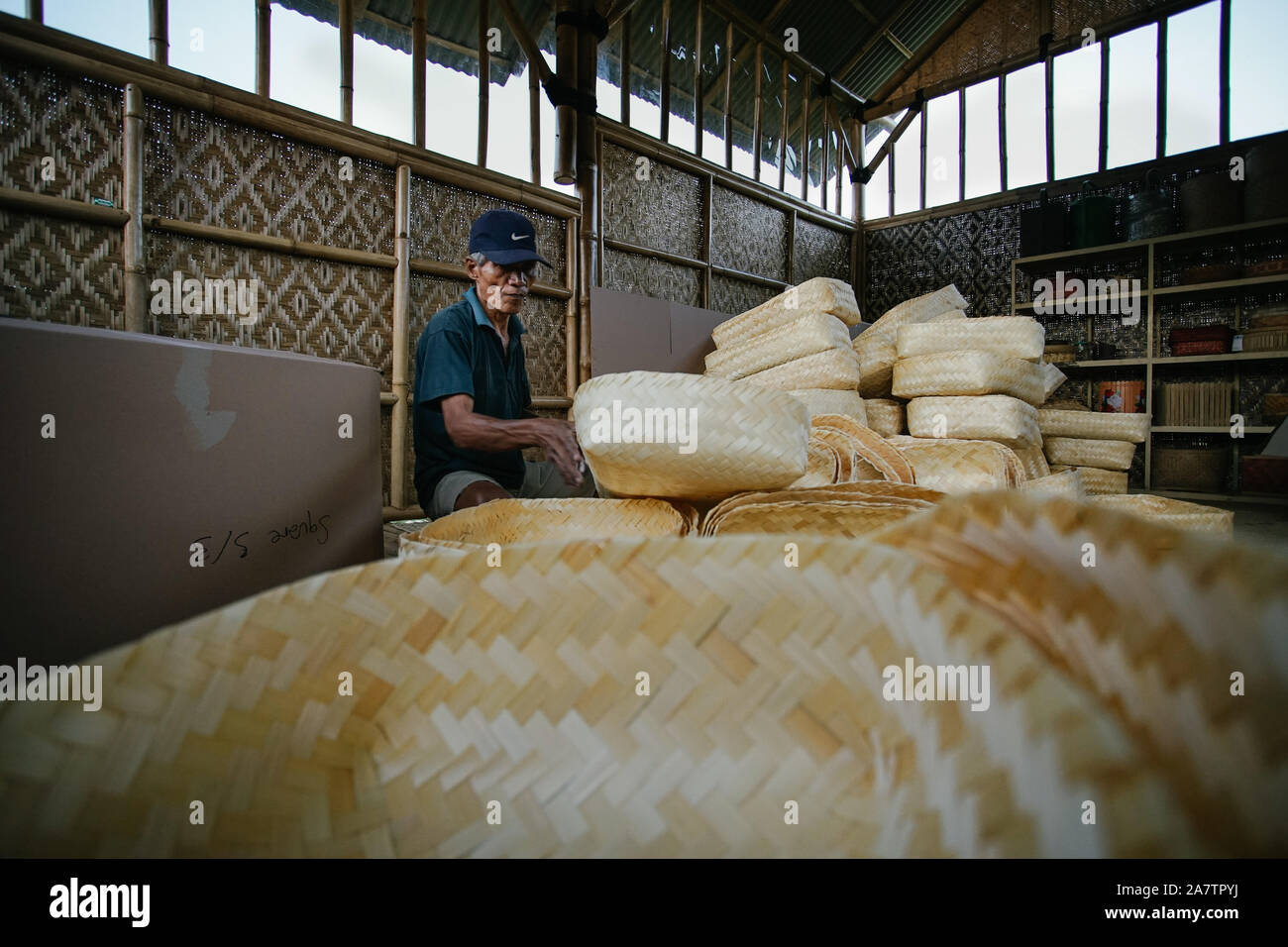 Workers packing traditional woven bamboo containers, "besek" into boxes ...