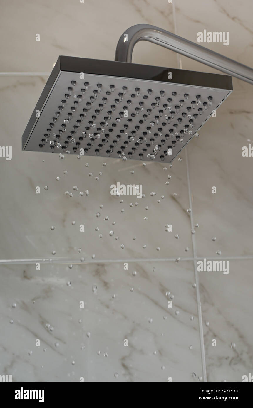 Drops of water falling from shower head in bathroom. Close up, copy ...