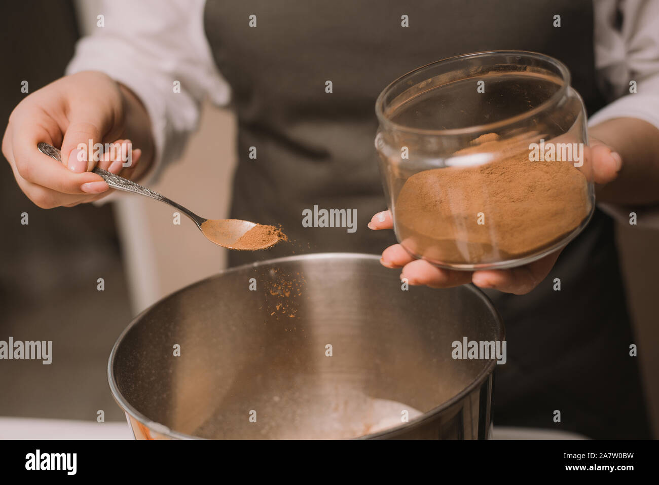 The cook girl pours brown cane sugar into a metal bowl. Cooking sweets ...